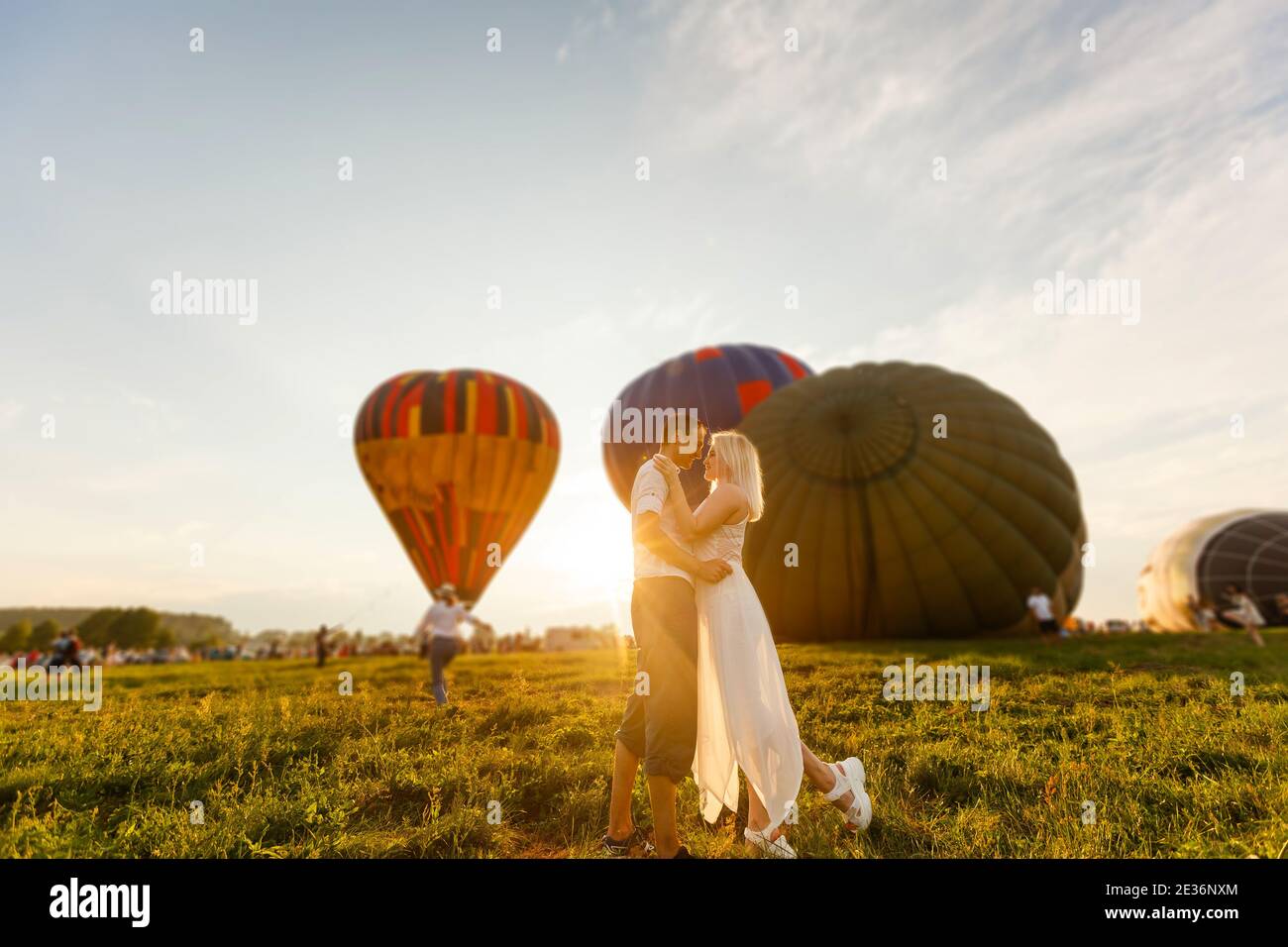 Beautiful romantic couple hugging at meadow. hot air balloon on a ...