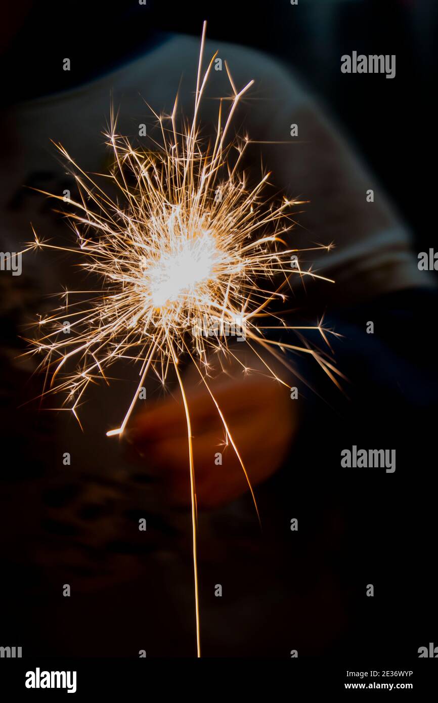 Burning Bengali fire on a dark background in a child's hand, make a ...
