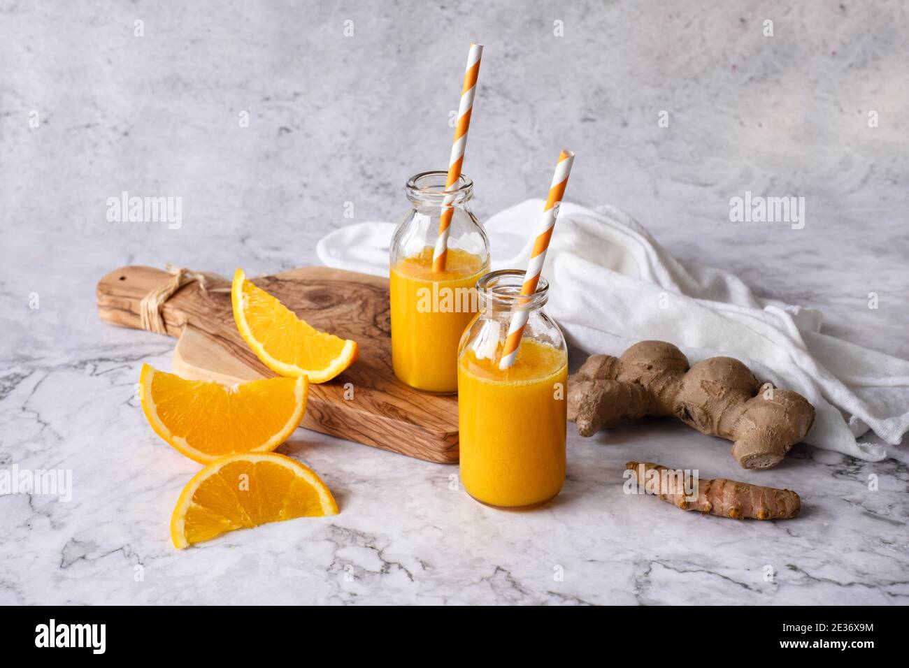 Two identical bottles filled with homemade ginger turmeric orange shot ...