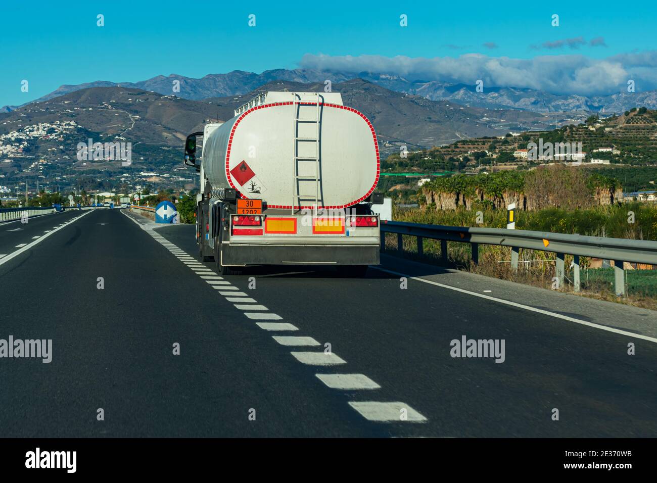Rear view of a tank truck carrying fuel and driving on the highway ...