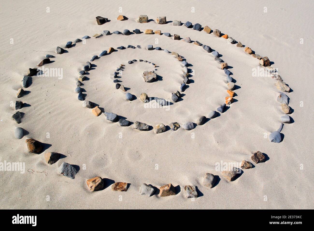 Spiral of stones on sandy beach Stock Photo - Alamy