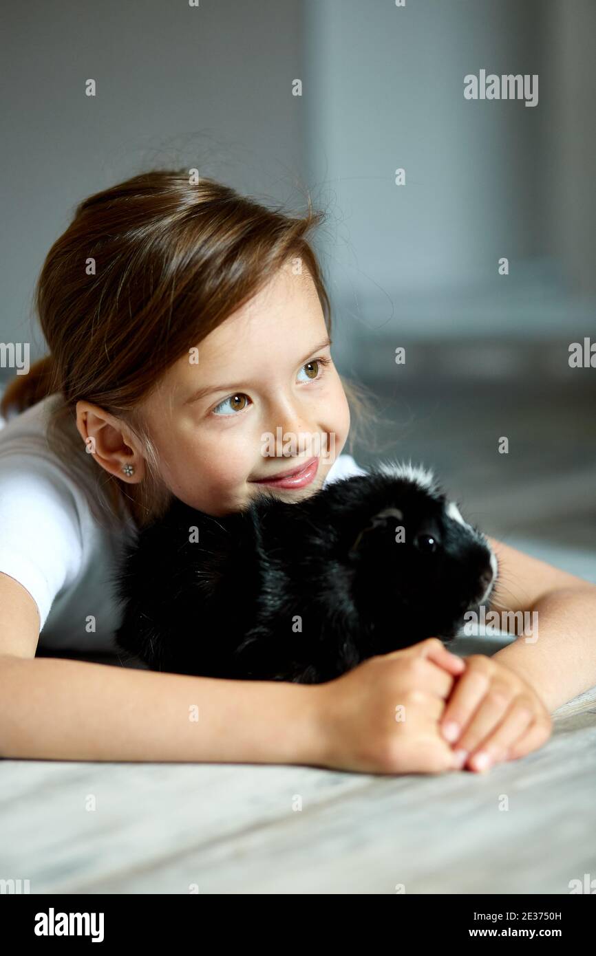 Portrait of happy smiling little girl hugging black guinea pig ...