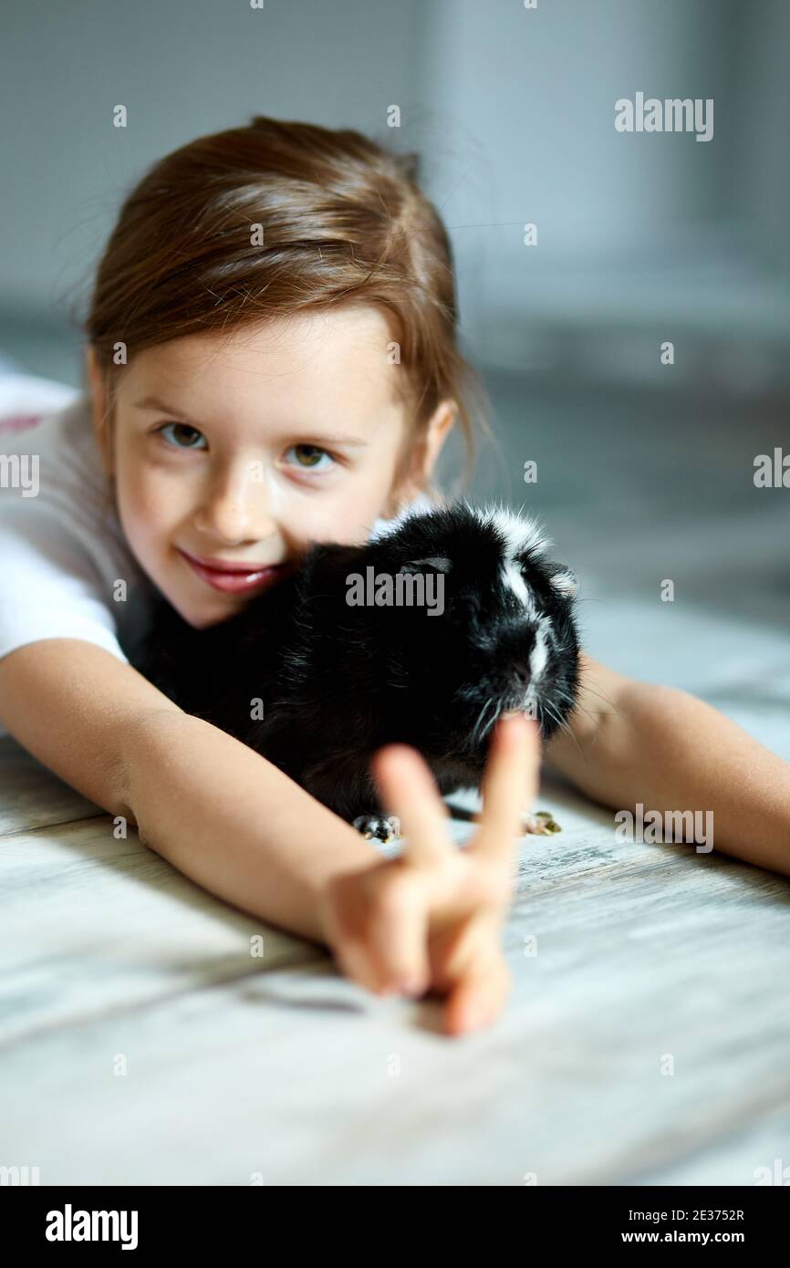 Portrait of happy smiling little girl hugging black guinea pig ...