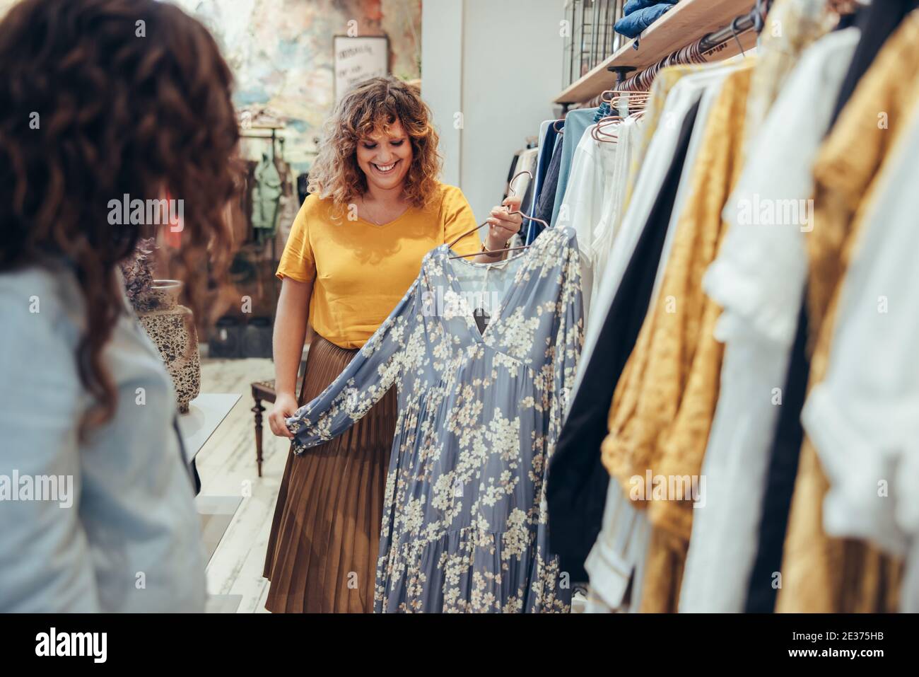 Shop assistant with a dress interacting with a female customer in ...