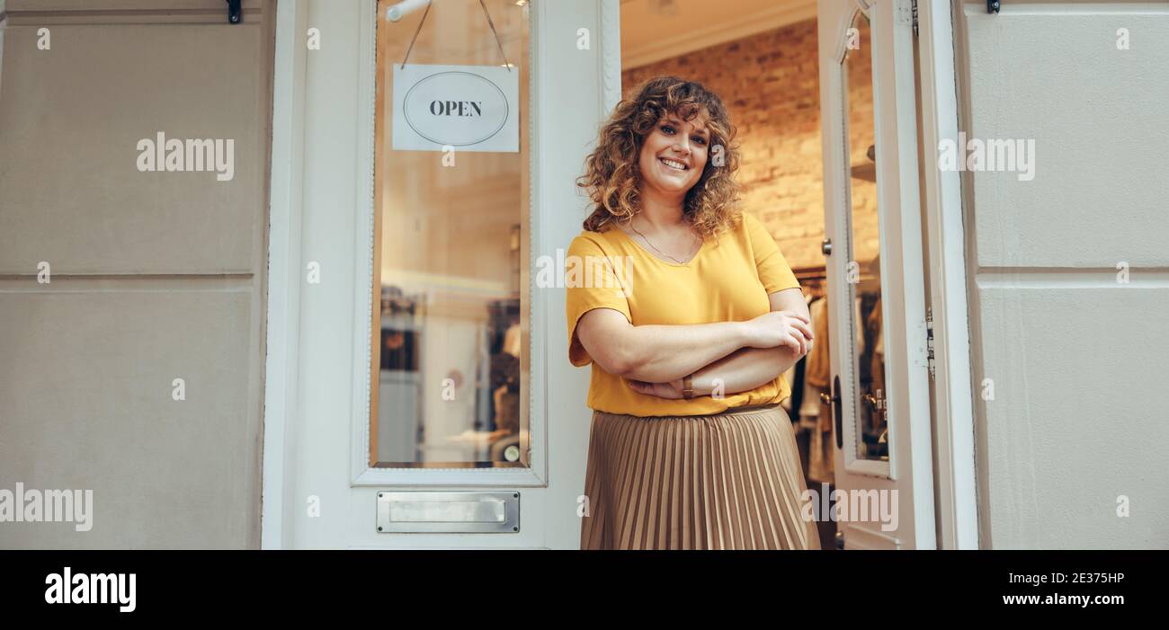 Woman leaning to entrance door of her store with OPEN sign hanging ...