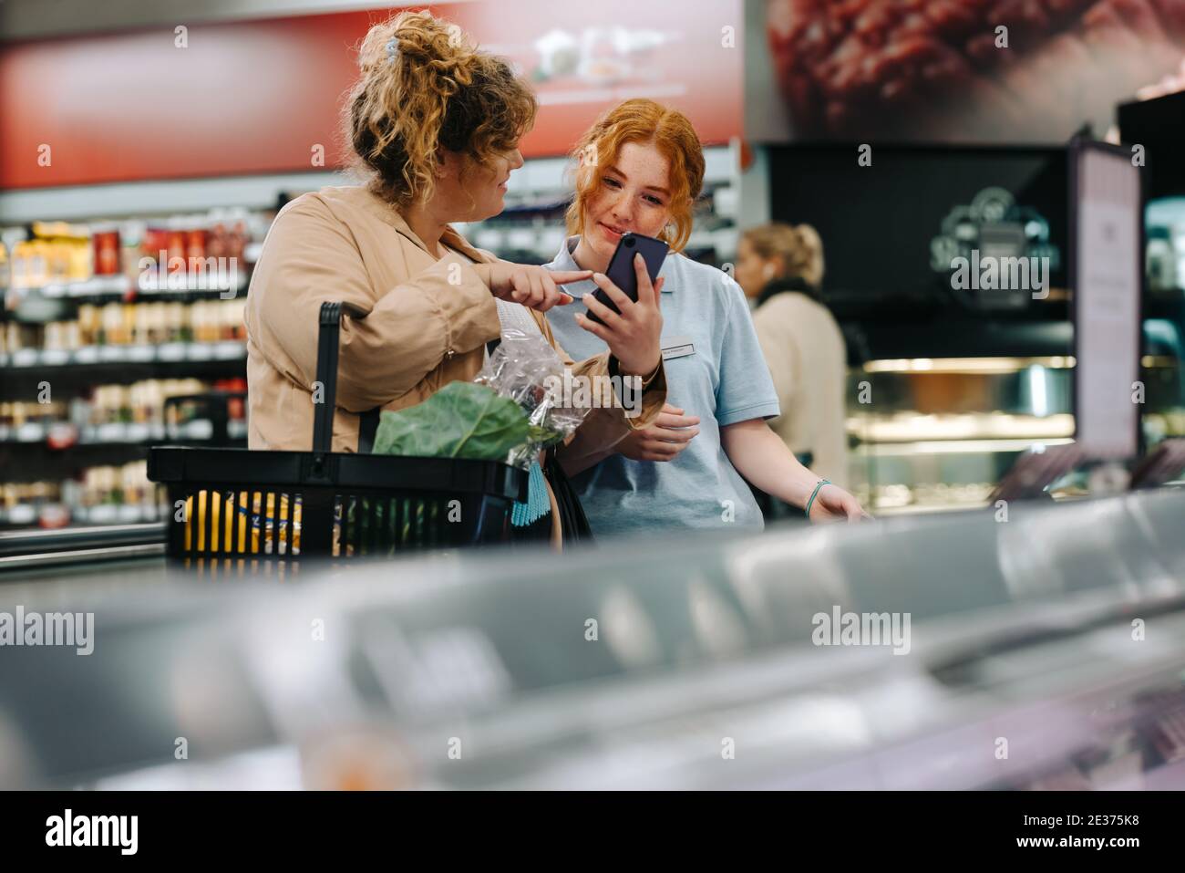 Female shopper showing her cell phone to store assistant and asking for ...