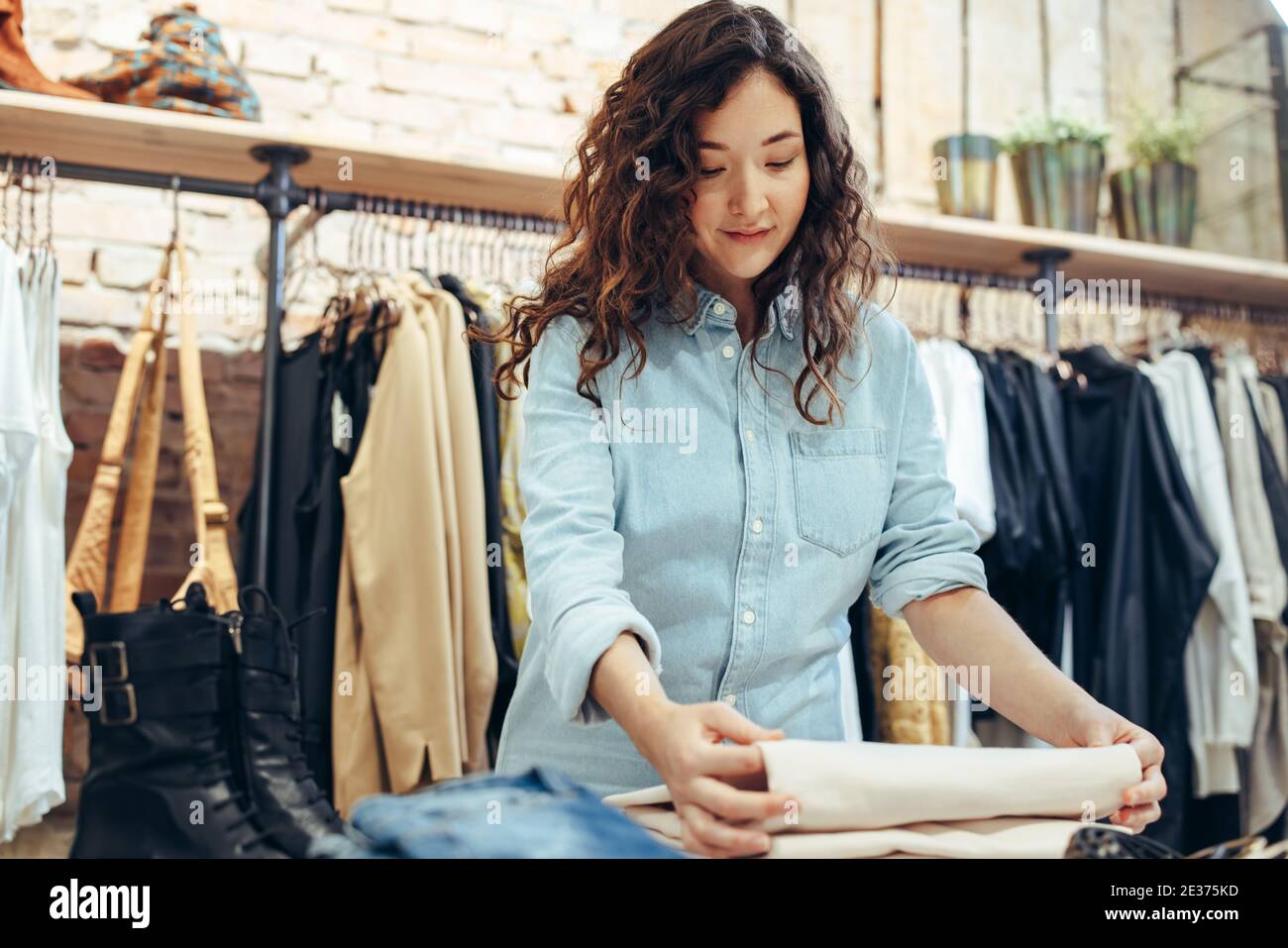 Female customer looking at a clothes in a store. Woman shopping in ...