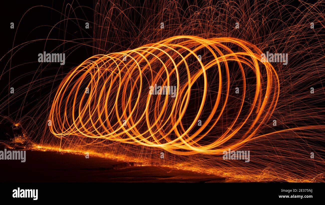 Swing fire Swirl steel wool light photography with reflex in the water ...