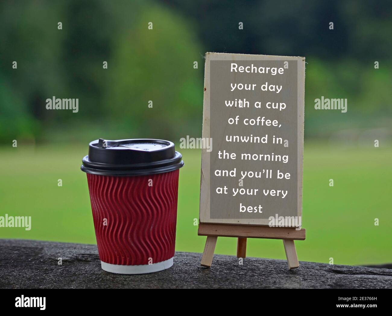 Red paper cup of coffee with text written on chalkboard and greenery ...
