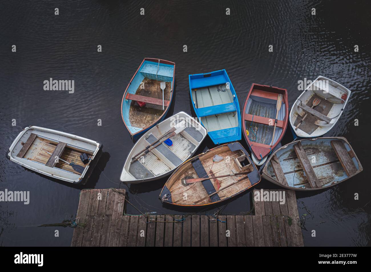 A gathering of old empty, vintage rowboats clustered together over dark ...