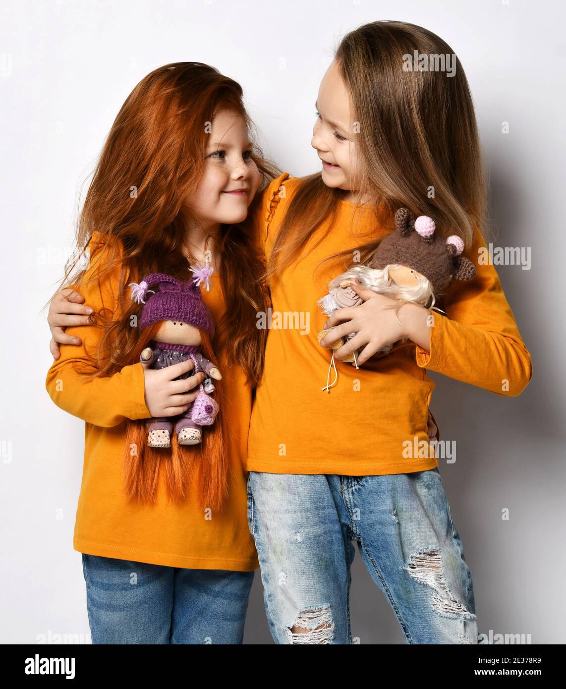 Portrait of two happy kid girls best friends in orange shirts standing ...