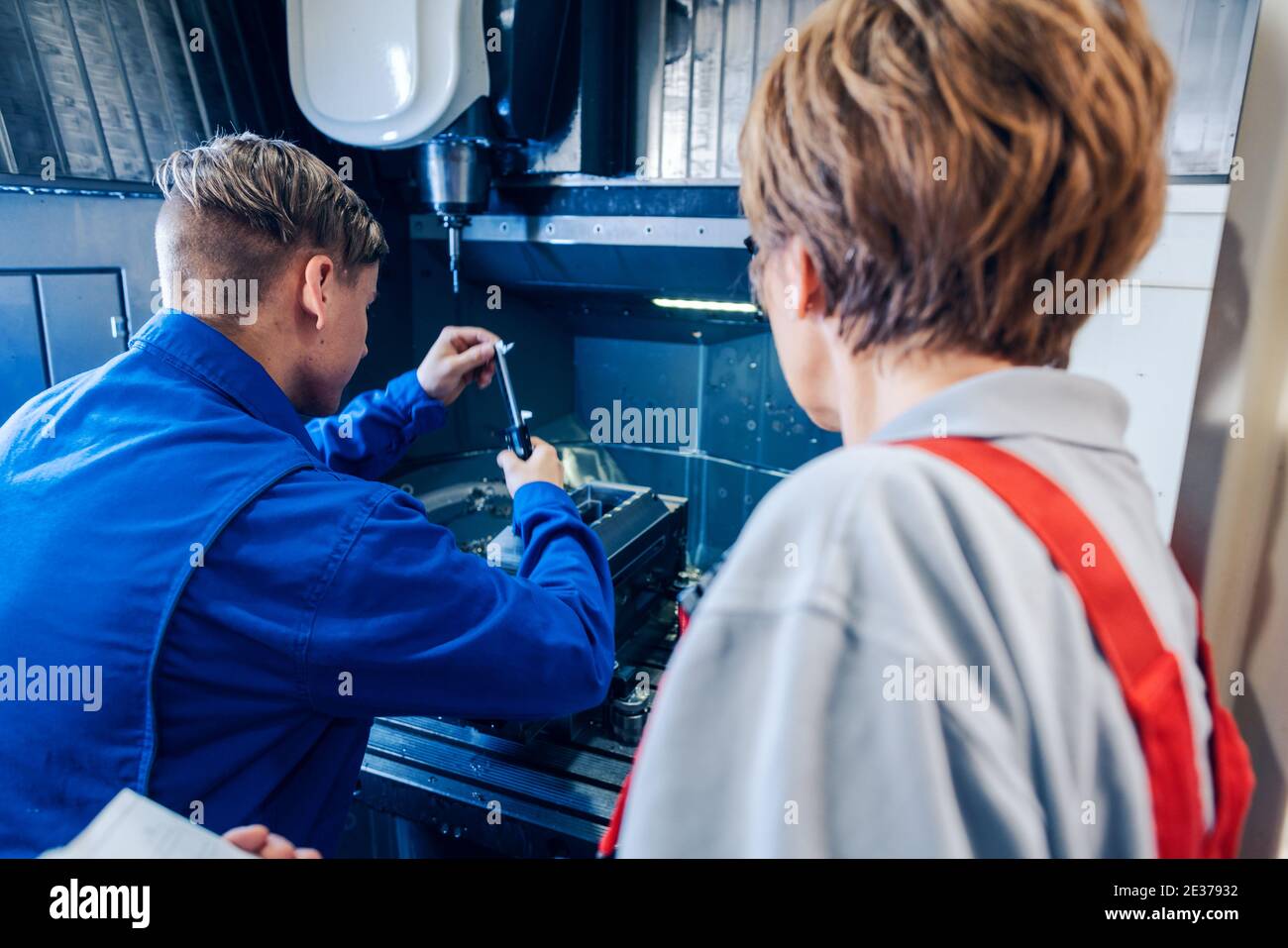 Supervisor watching young worker changing setup of lathe machine Stock ...