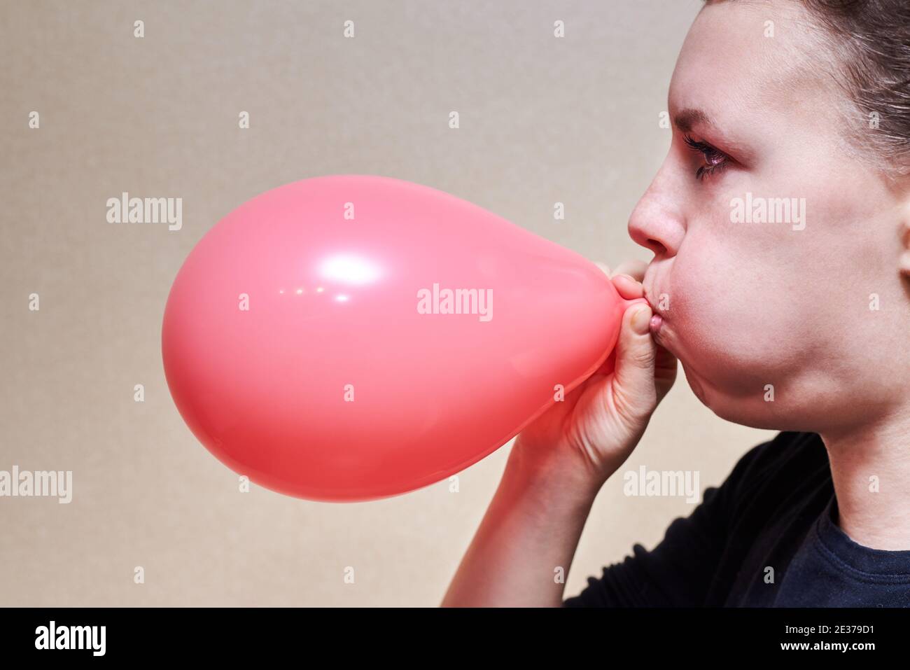 Young woman inflate a red balloon, the theme of holidays and parties ...