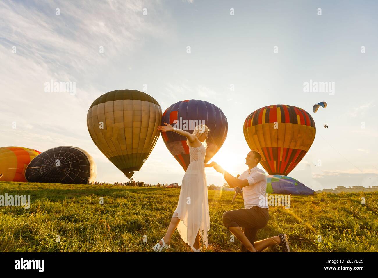 Beautiful romantic couple hugging at meadow. hot air balloon on a ...