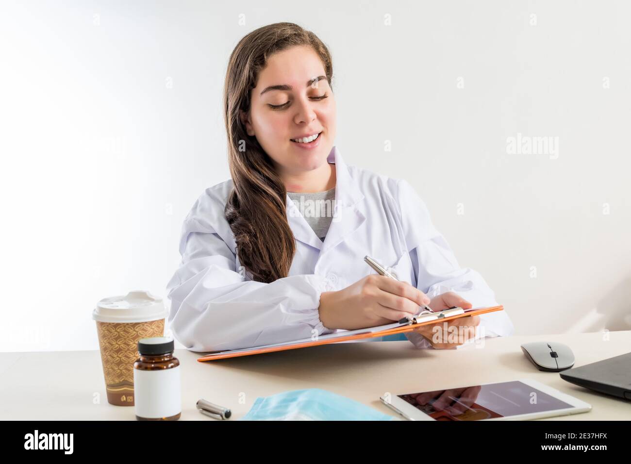 A young female professional doctor sitting in her consulting room ...