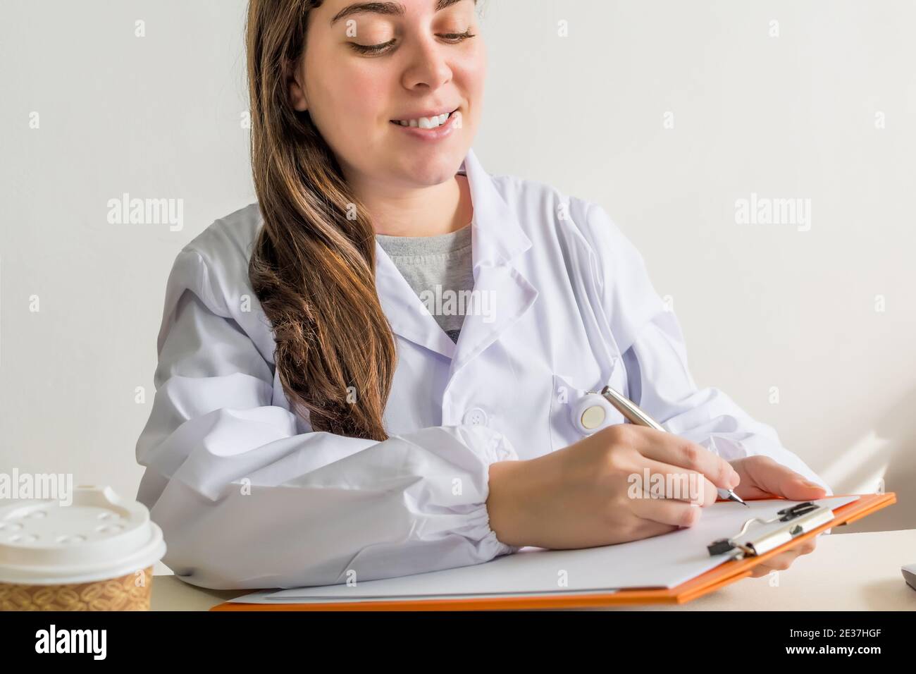 A young female professional doctor sitting in her consulting room ...