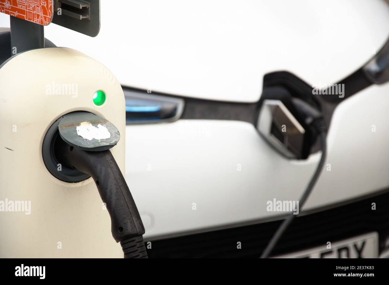 Electric car plugged in and charging at roadside charging point Stock ...