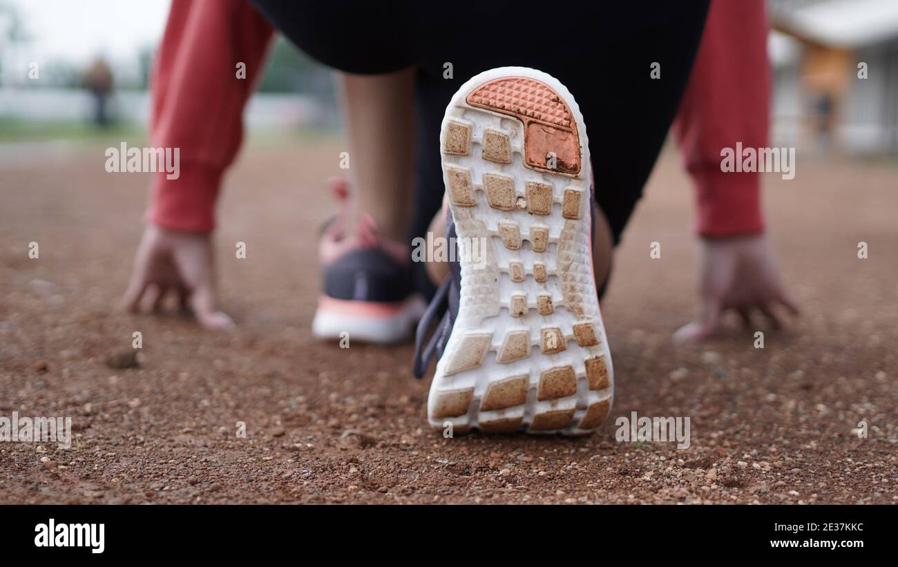 Close up shoes of woman athlete getting ready to start running on track ...