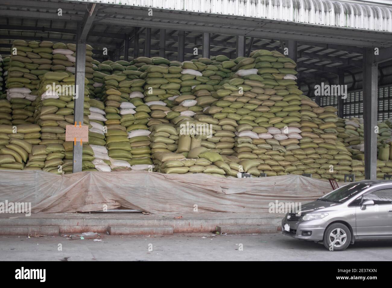 Green and white bags of rice stacked tall at a local storage warehouse ...