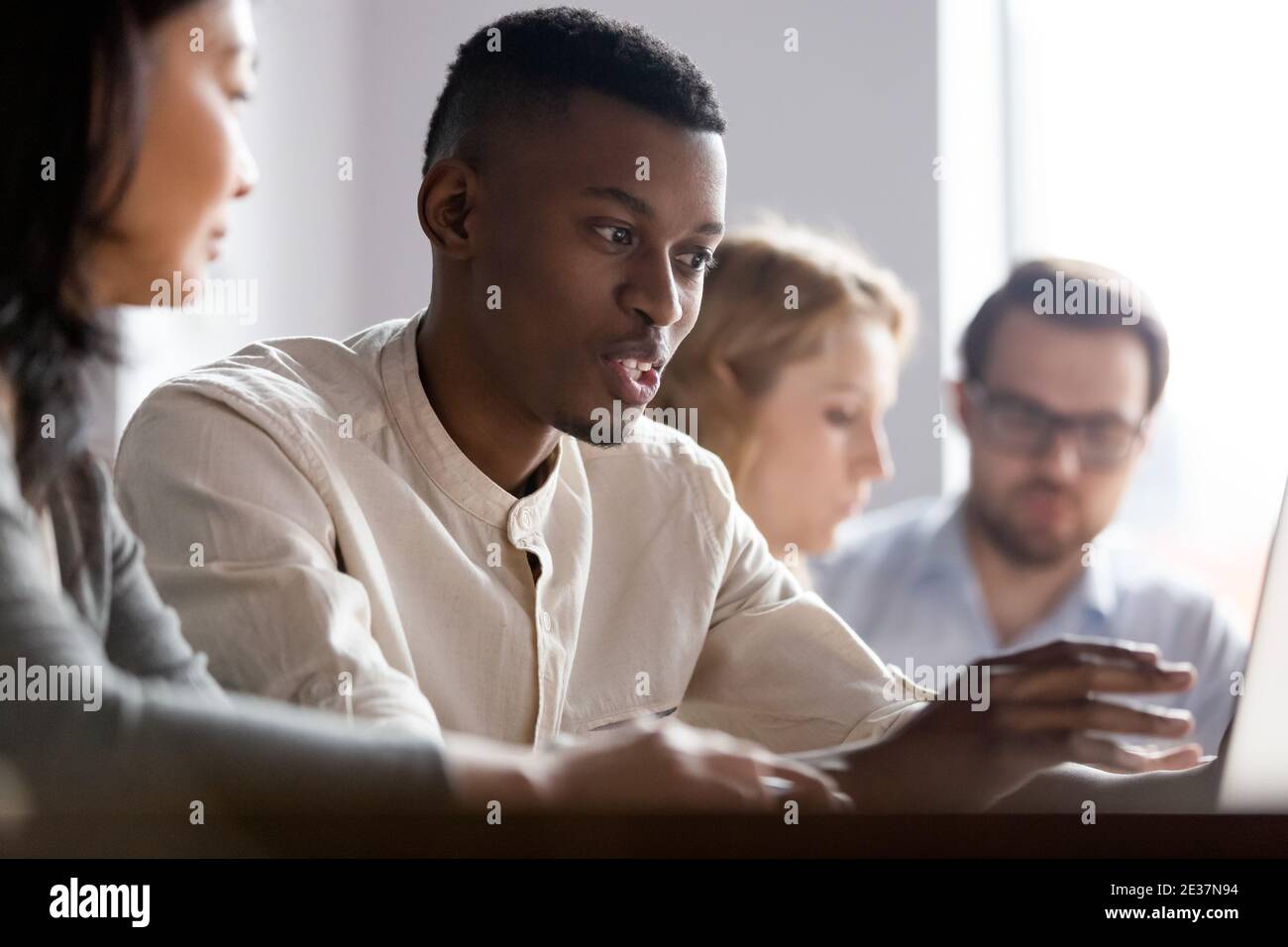 Focused young african employee working on computer with old colleague ...