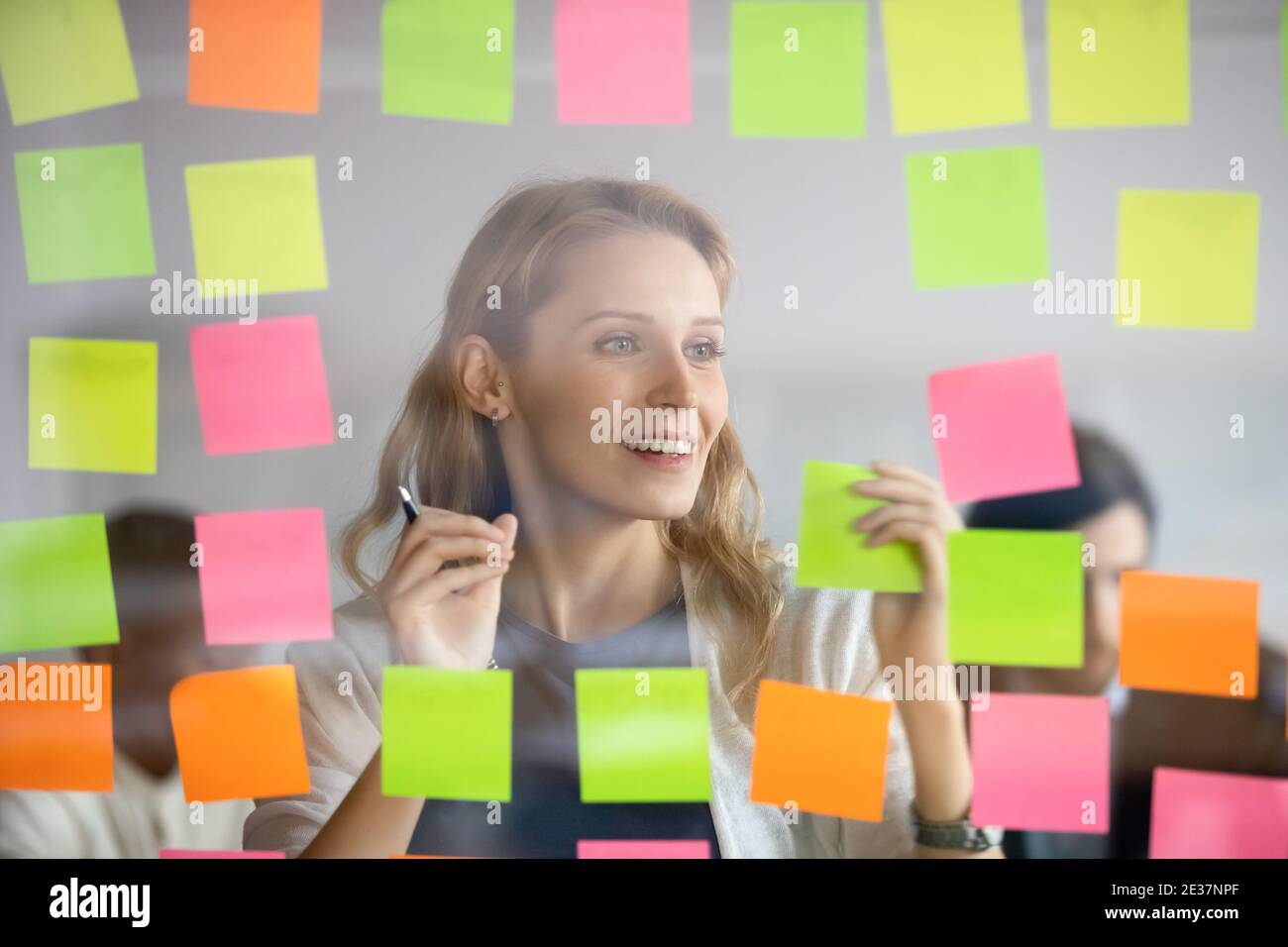 Smiling motivated young female employee managing working tasks Stock ...