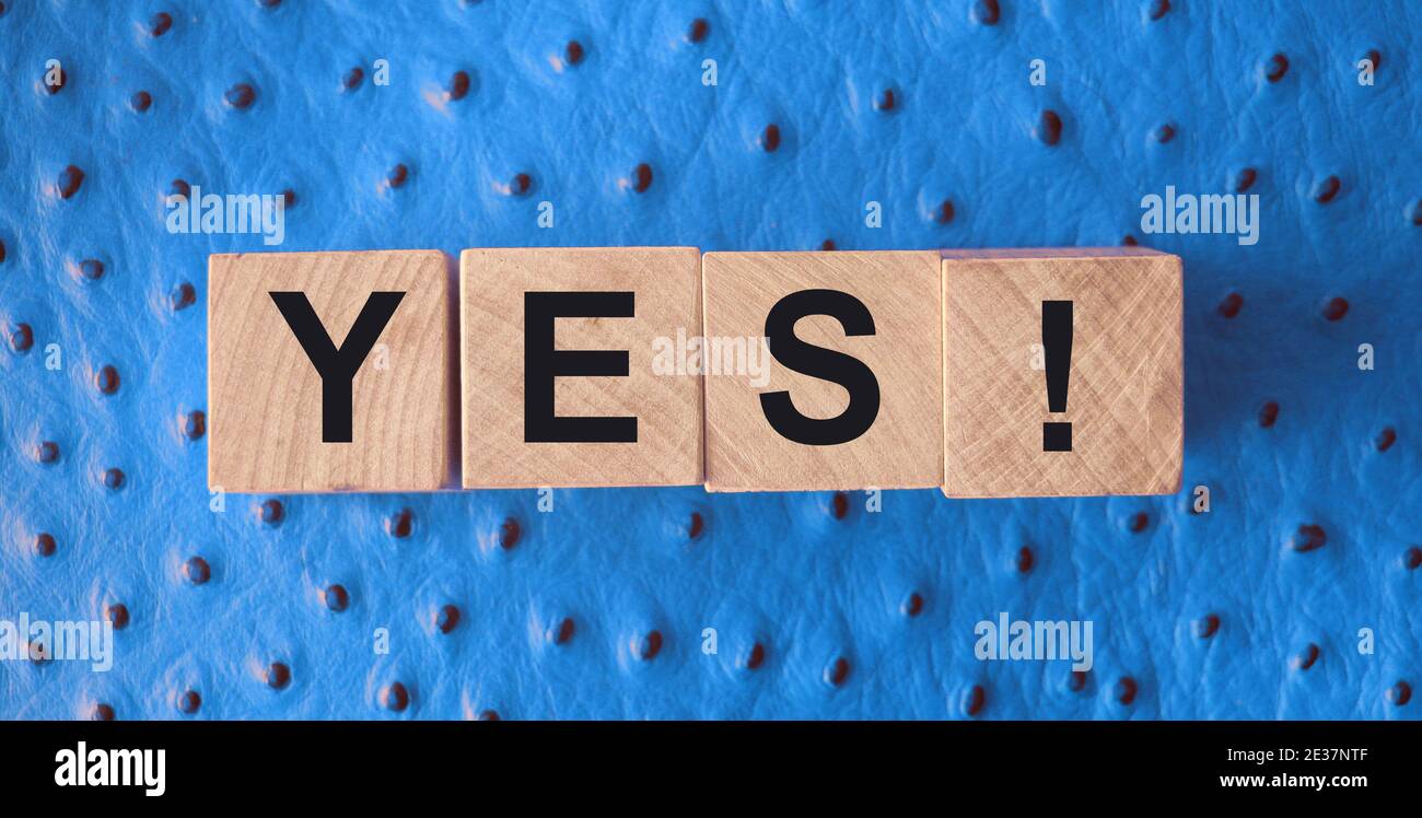 The word Yes written in black letters on wooden blocks. on red leather ...