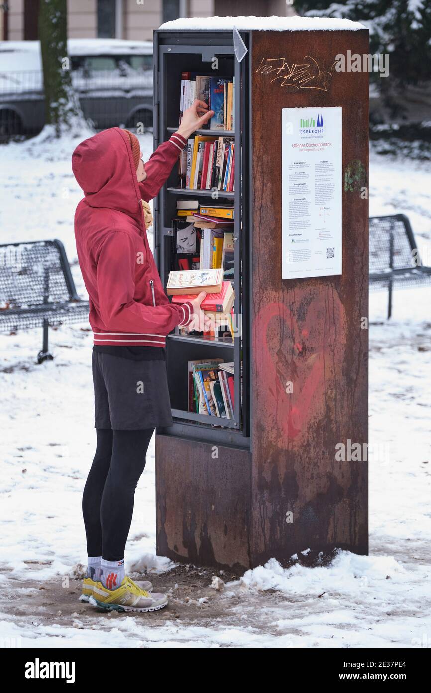 Young man takes a book out of a public bookcase Stock Photo - Alamy