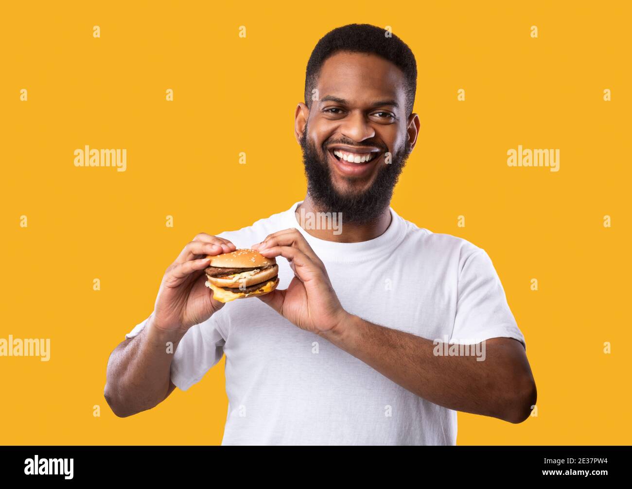 Black man posing holding burger smiling to camera, studio shot Stock ...