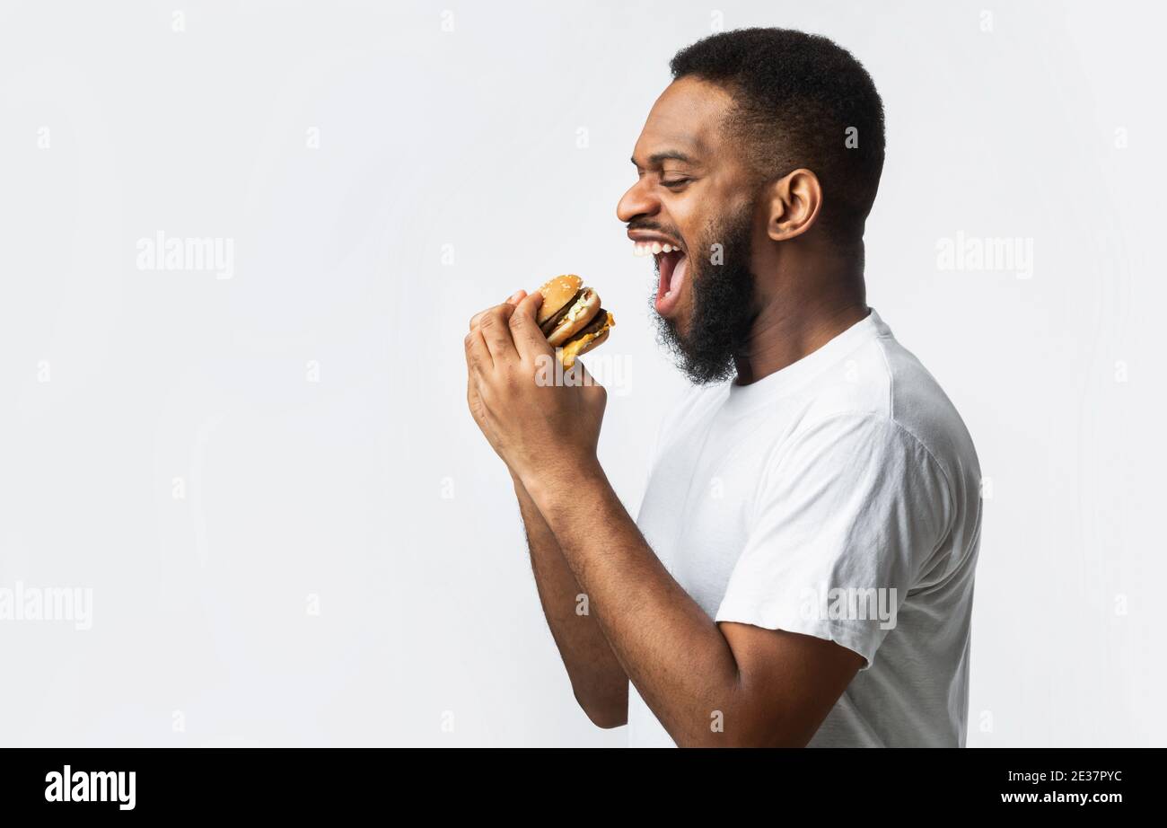 Side View Of Hungry Black Man Eating Burger, White Background Stock ...