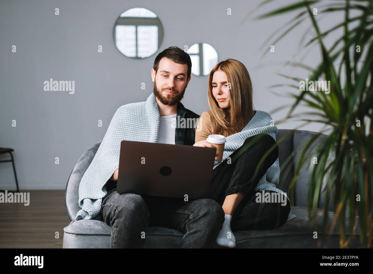 Young couple using laptop computer and resting on the sofa at home ...