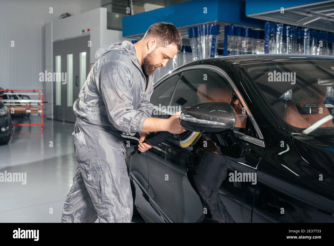 Worker polishing car with special grinder and wax from scratches at the ...