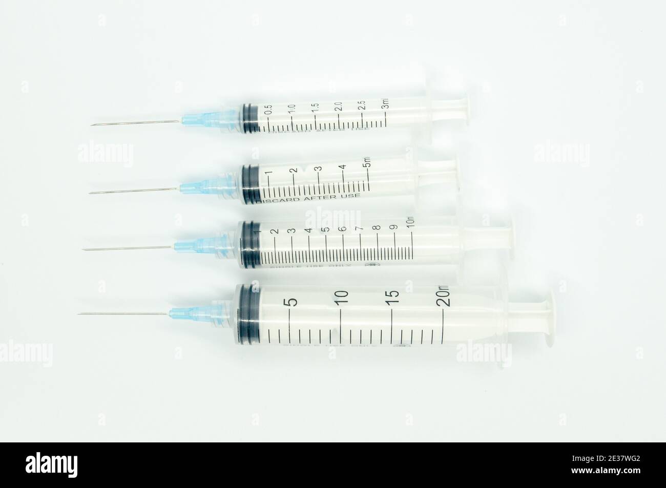 A top view of syringe needles in different sizes, on a white surface ...