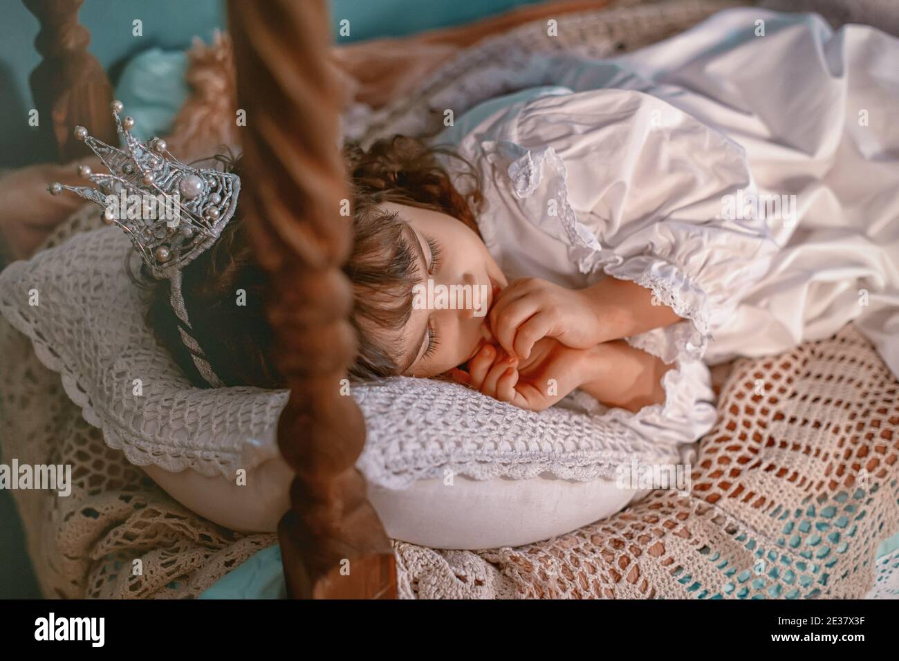 A beautiful little princess girl is sleeping on an openwork pillow ...