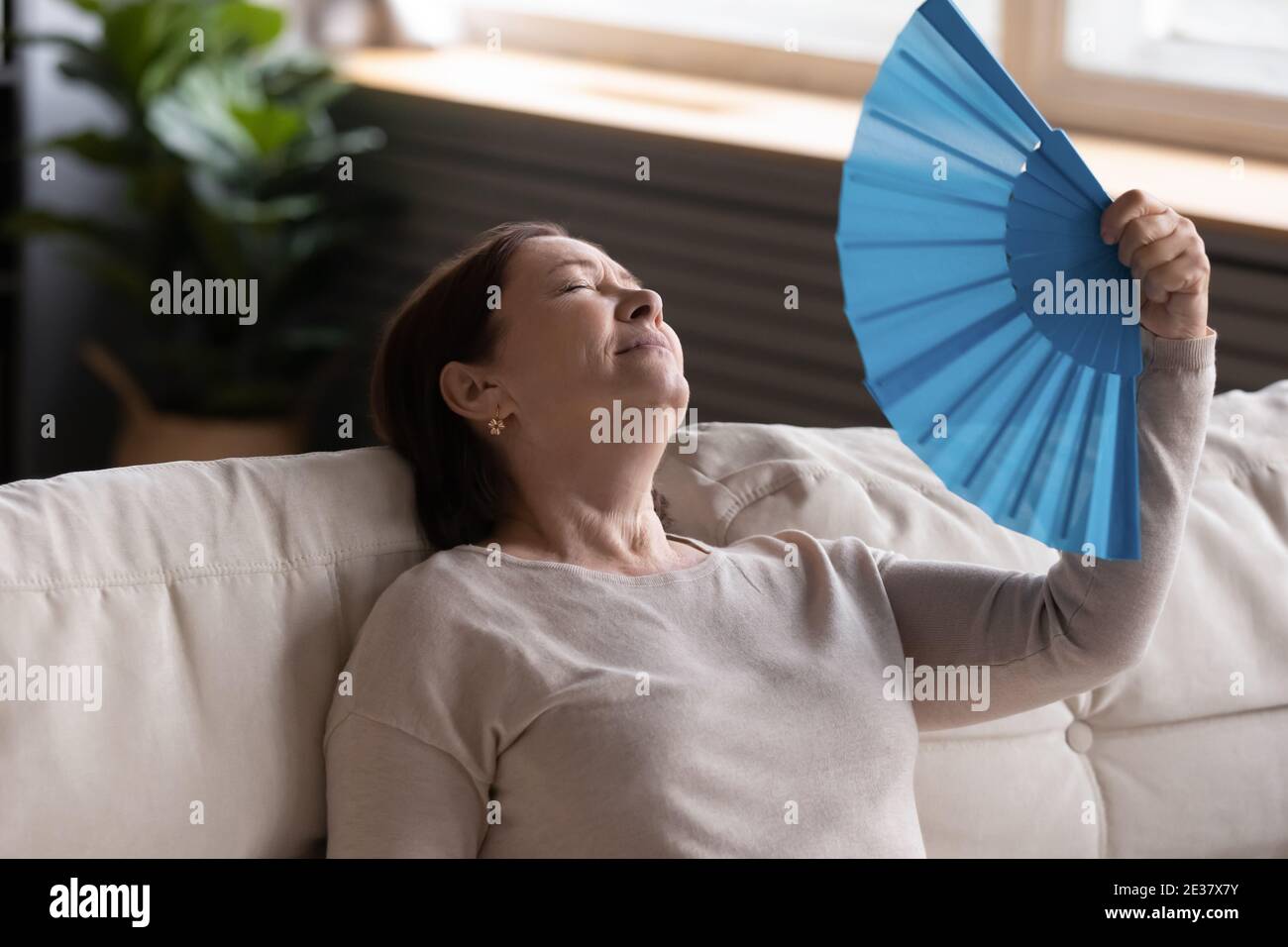 Close up exhausted middle aged woman waving paper fan Stock Photo - Alamy