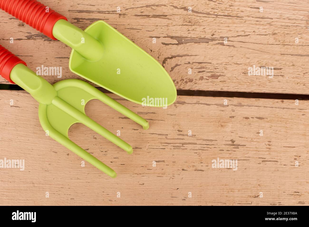Light green garden hand tools, a shovel and a rake with orange handles ...