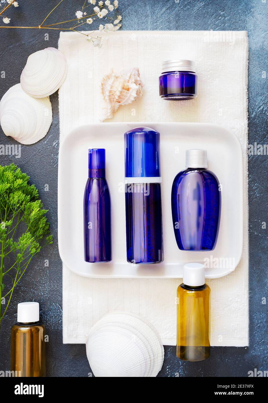 Beauty mock-up bottles for branding and label. Blue cosmetic bottles on a white towel with ...