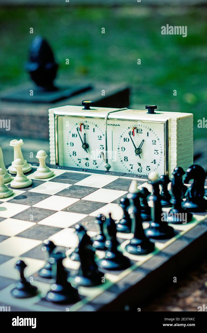 Chess board with pieces and clock on wooden desk In connection with the ...