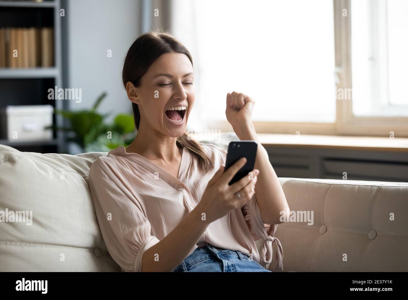 Close up overjoyed woman holding phone, screaming with joy Stock Photo ...