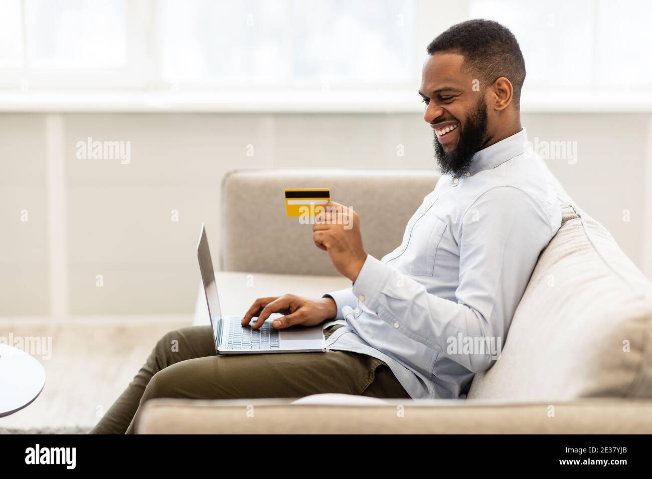 Black man using computer and debit credit card at home Stock Photo - Alamy