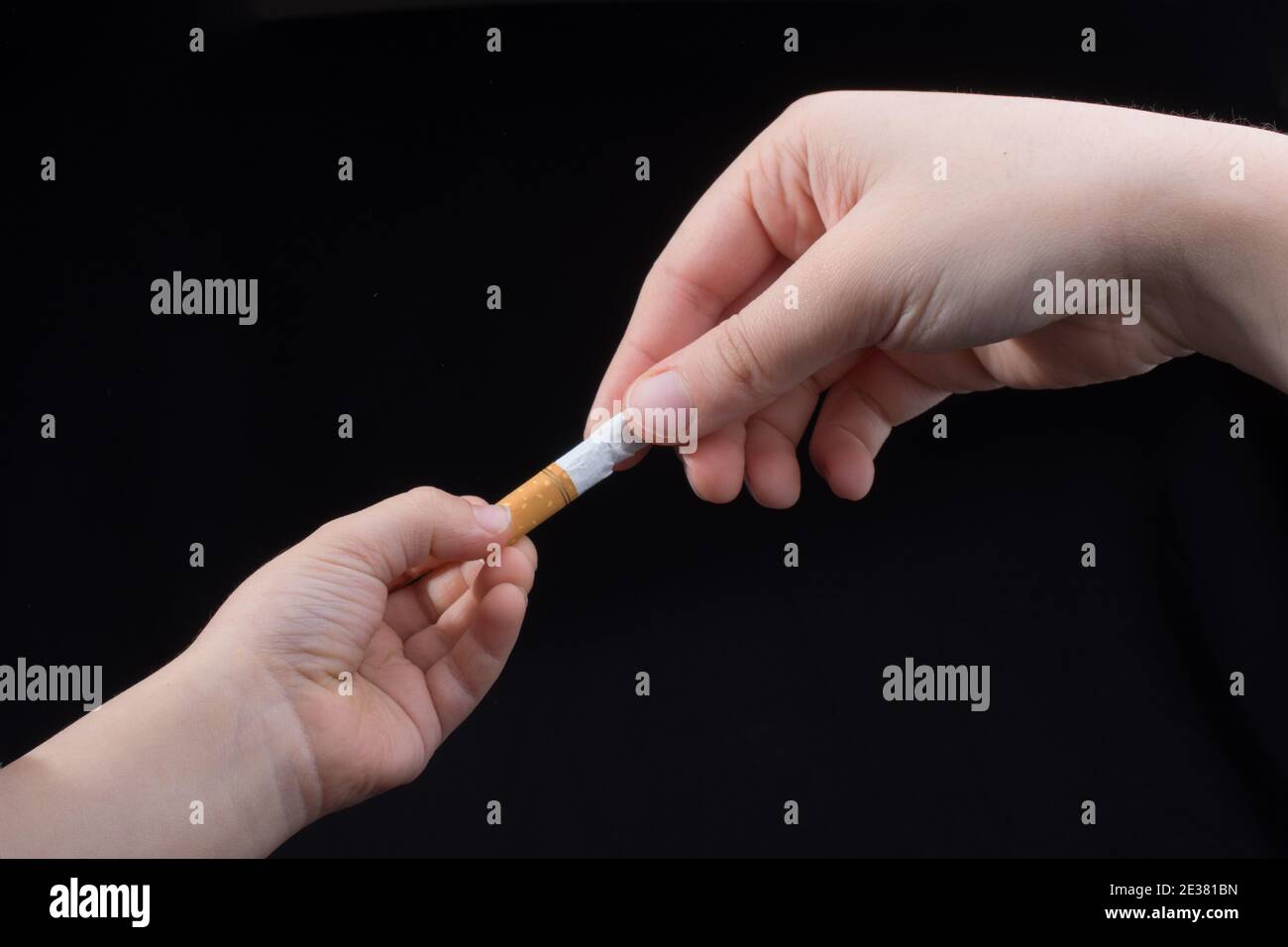 Hand is giving out cigarette on a black background Stock Photo - Alamy