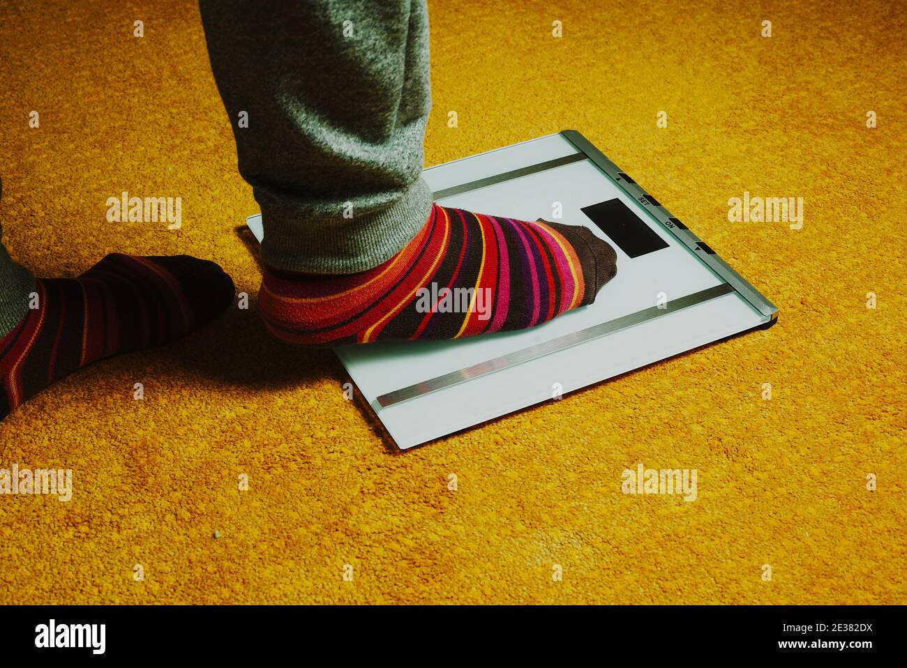 man feet with colorful socks step on the weight scale Stock Photo - Alamy