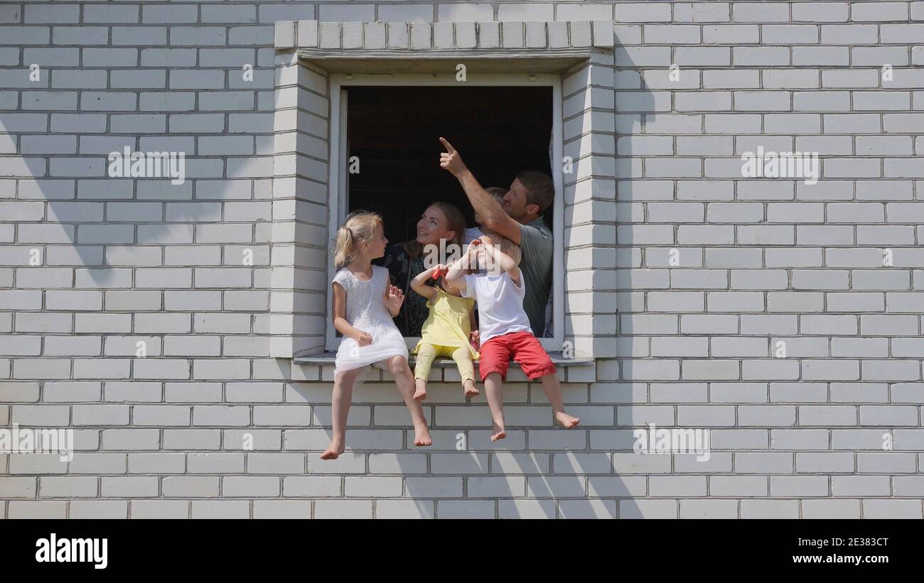 A friendly family appears in the window of their house Stock Photo - Alamy