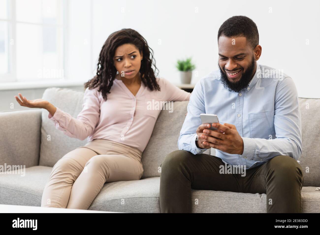 Angry Black Woman Looking At Boyfriend, Man Using Phone Stock Photo - Alamy