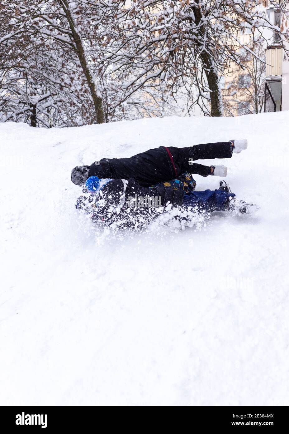 Two boys fall from a tubing on a snow slide Stock Photo - Alamy