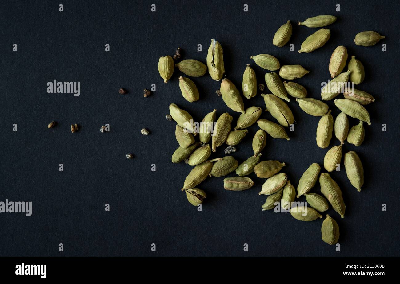 Close up photo of Cardamom pods and seeds pile on the matt black ...