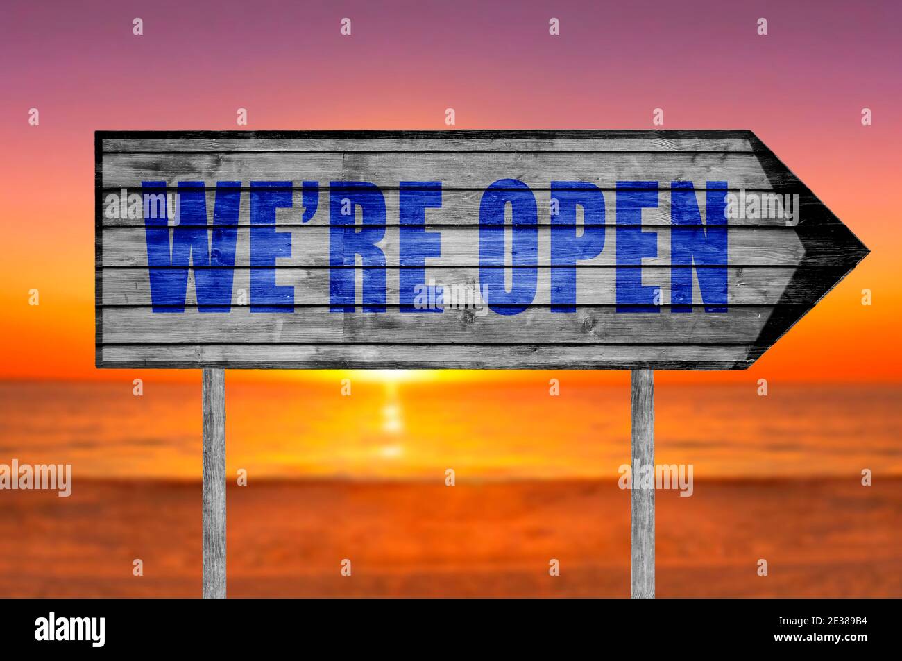 We're open wooden sign with on a beach background Stock Photo - Alamy