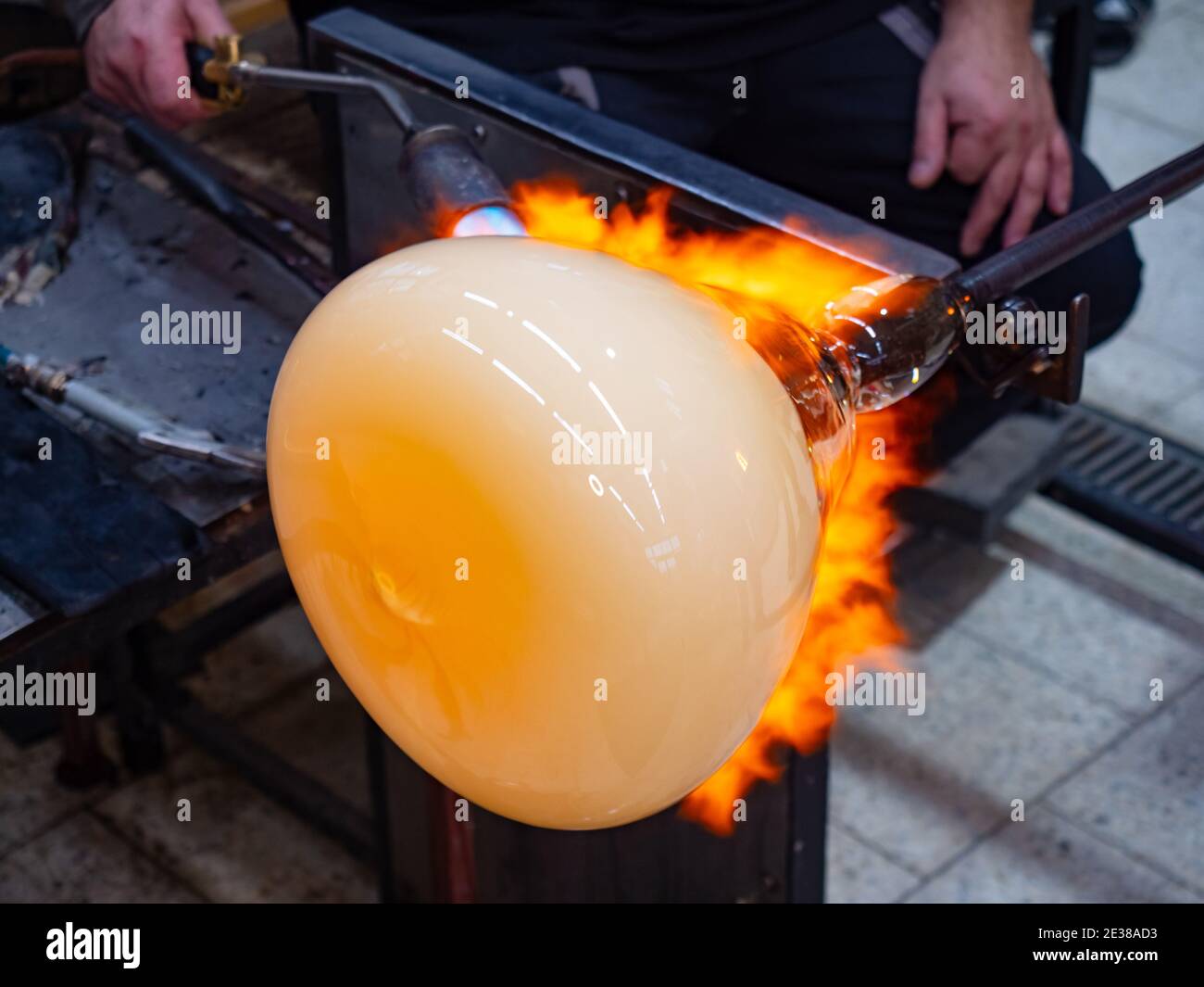 Glass artist forms the scorching glass with heats it with a gas burner ...