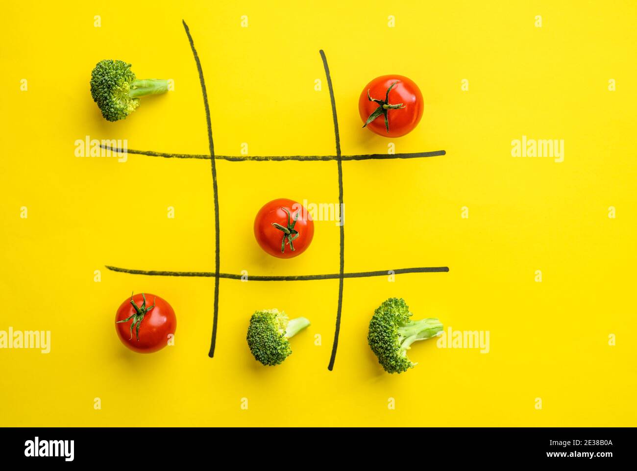 Vegetable cross-zero game on yellow background Stock Photo - Alamy
