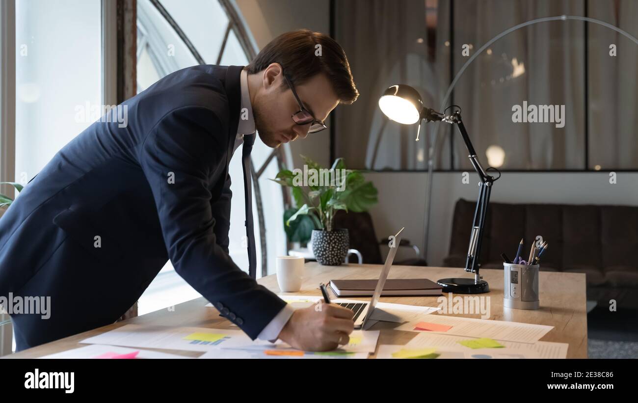 Close up confident businessman wearing glasses writing notes on ...