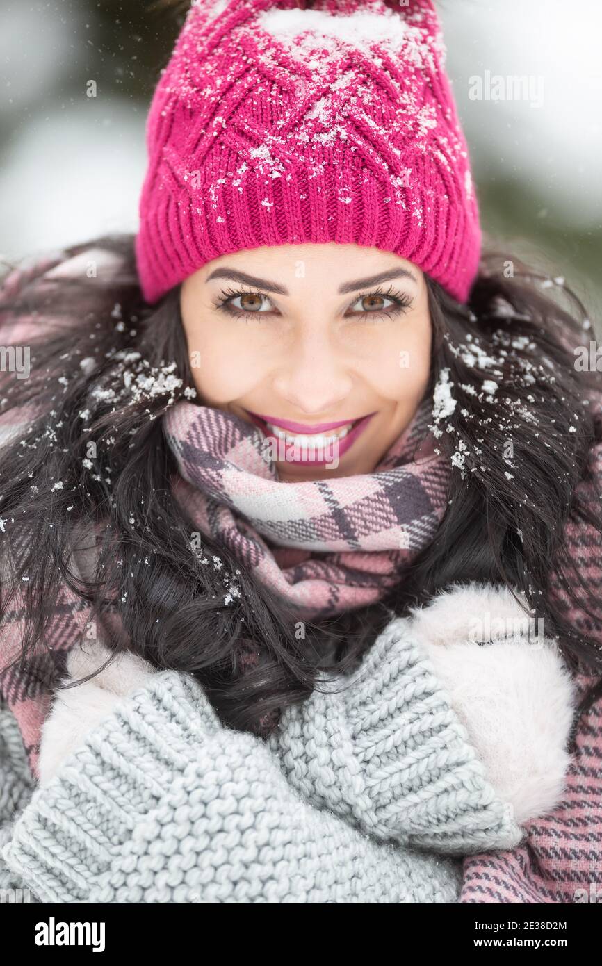 Beautiful woman covered in snow cuddles herself in winter cold smiling ...